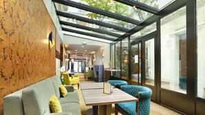 Um interior moderno com teto de vidro, um sofá com almofadas amarelas e uma mesa com um quadro emoldurado.