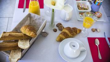 Uma mesa de café da manhã com croissants, suco e um arranjo floral.