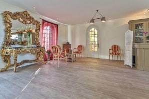 Um quarto espaçoso com um espelho grande e trabalhado, um aparador de madeira e algumas cadeiras.