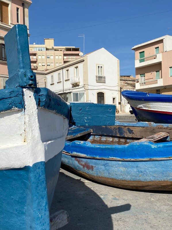 Uma fileira de barcos com pintura azul e branca, estacionados sobre uma superfície de concreto.