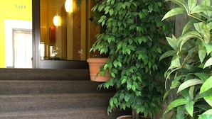 Degraus de pedra que levam à entrada de um hotel, com plantas em vasos de ambos os lados.