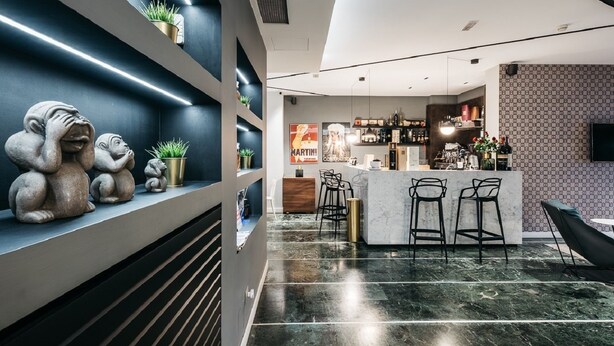 Uma área de bar moderna com piso de mármore, banquetas e balcão.