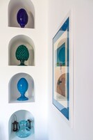 Uma parede com quatro prateleiras, cada uma exibindo um objeto decorativo diferente.