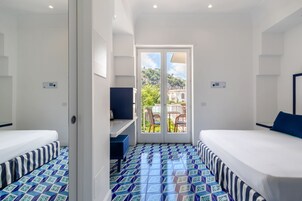 Quarto de hotel com duas camas, uma escrivaninha e vista para o exterior.
