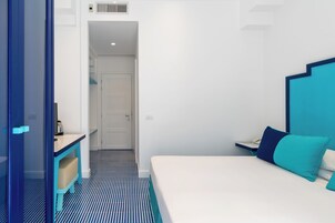 Quarto de hotel com uma cama, uma escrivaninha e uma cadeira.