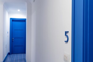 Um corredor com uma porta azul e o número 5 na parede.