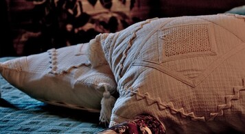 Uma cama com manta e almofadas estampadas.