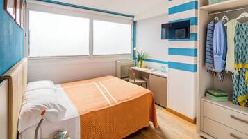 Um quarto com uma cama, uma escrivaninha, uma cadeira e um guarda-roupa.