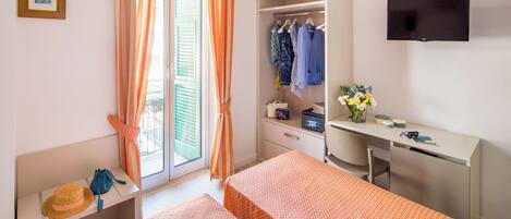Quarto com cama, escrivaninha, guarda-roupa e televisão.