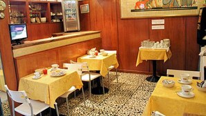 Um restaurante com mesas montadas para refeições, uma máquina de venda automática e uma pintura decorativa na parede.