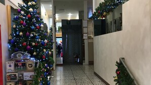 Uma escadaria decorada com uma árvore de Natal enfeitada com enfeites e luzes coloridas, que leva a um quarto com piso ladrilhado.