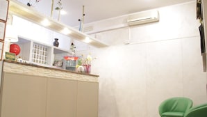Uma área de recepção com balcão, uma cadeira verde e um refrigerador Coca-Cola.