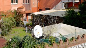 Um edifício de vários andares com fachada vermelha, uma antena parabólica e uma escadaria que leva à entrada.
