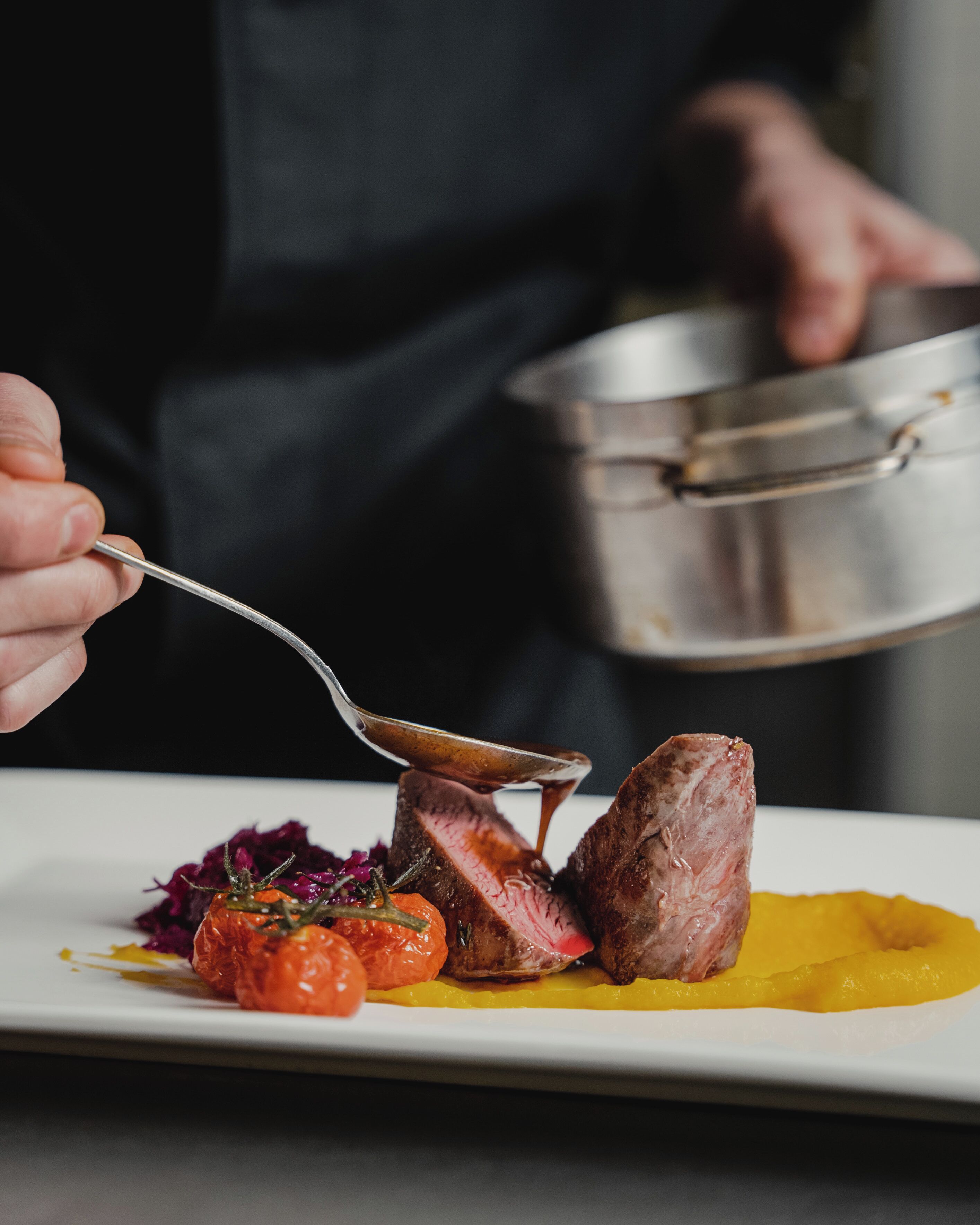 Uma pessoa servindo um prato com bife e legumes.
