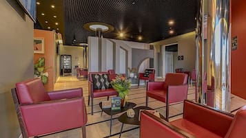 Um saguão com assentos vermelhos, uma mesa de centro e uma planta.