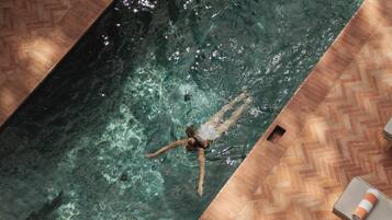 Uma piscina com padrão de mosaico em espinha de peixe e espreguiçadeiras com toalhas.