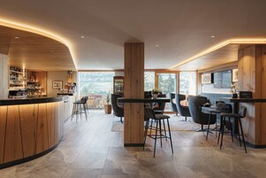 Uma área de bar moderna com detalhes em madeira, balcão e assentos.