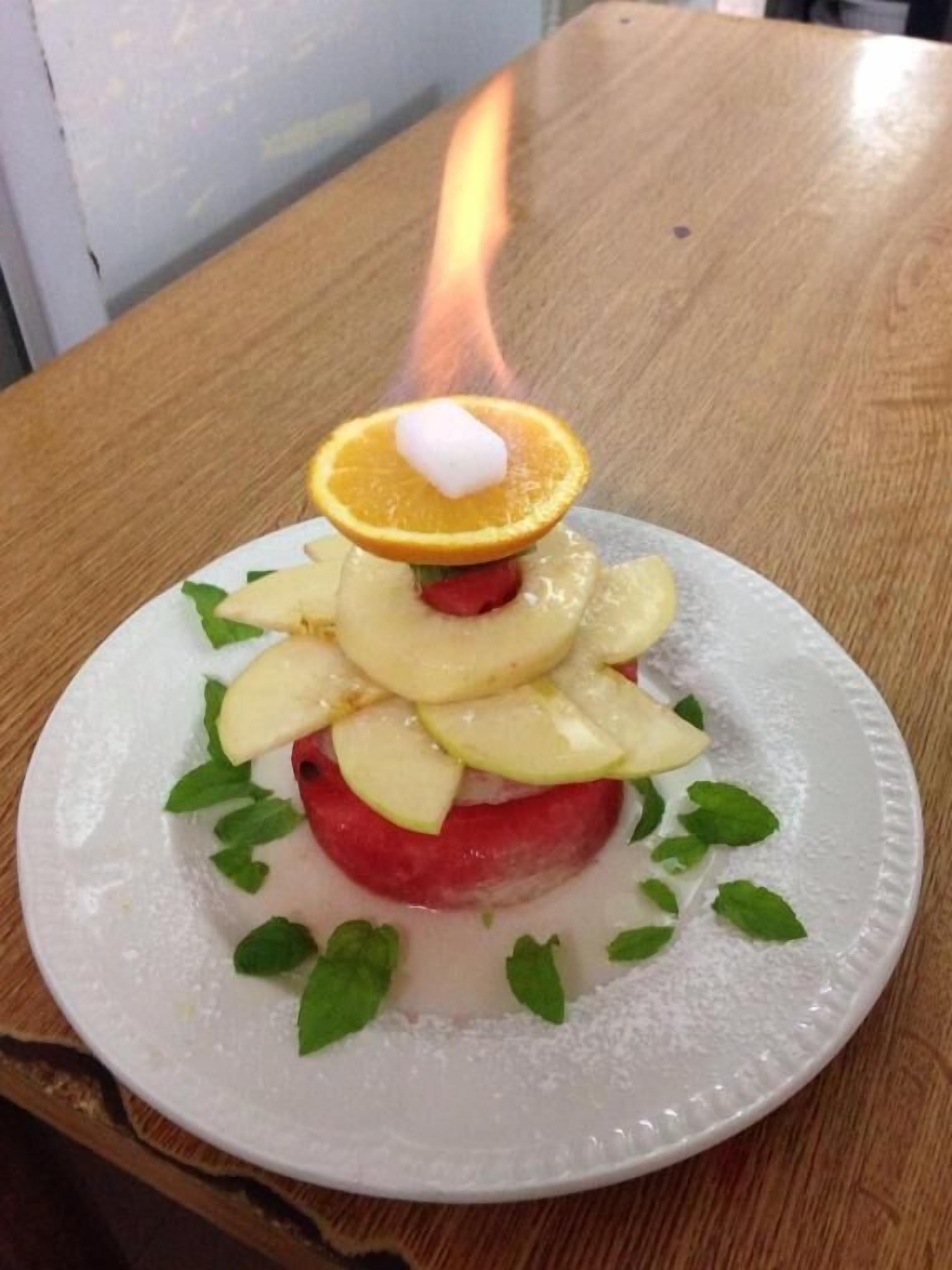 Uma travessa com uma composição de frutas e uma vela acesa.