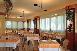 Um restaurante com várias mesas, cada uma com toalhas brancas e jogos de mesa numerados.