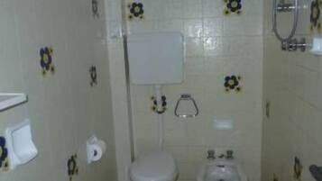Casa de banho pequena com sanita, bidé e chuveiro.