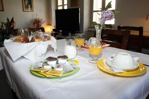 Mesa de café da manhã com croissants, suco e xícaras de café.