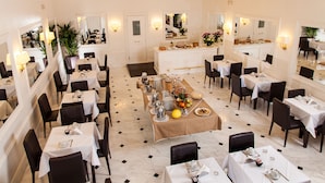 Uma sala de jantar espaçosa com várias mesas, cadeiras e um buffet central.