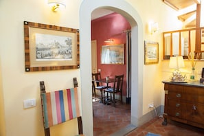 Um corredor com um armário de madeira, um quadro emoldurado e uma toalha listrada sobre uma cadeira.