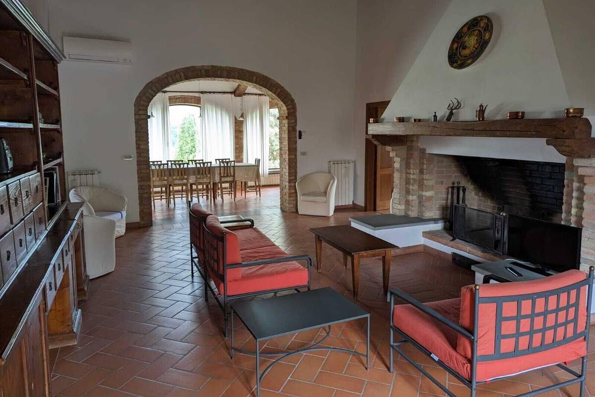 Uma sala de estar ampla com lareira, mesa de jantar e sofá.