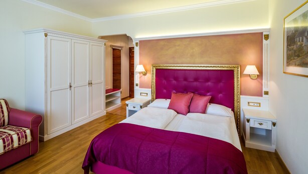 Quarto com uma cama grande, duas mesas de cabeceira, um guarda-roupa e uma cadeira.