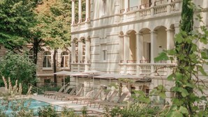 Um edifício grande com piscina, espreguiçadeiras e vegetação.