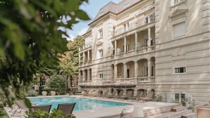 Um edifício grande com piscina, área de estar ao ar livre e escadaria que leva à entrada.