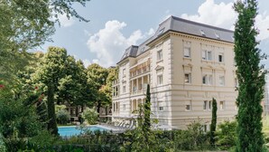 Um edifício com vários andares, piscina, vegetação e árvores ao redor.