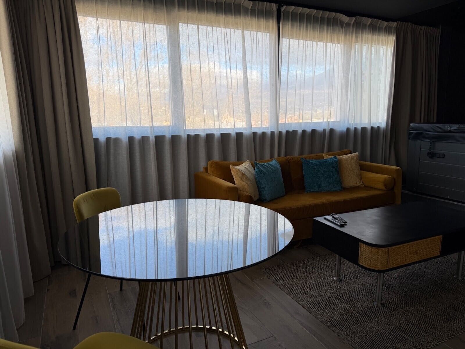 Um quarto com uma mesa redonda, um sofá e uma cadeira.