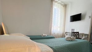 Quarto de hotel com duas camas, uma televisão na parede e uma mesa com cadeiras.