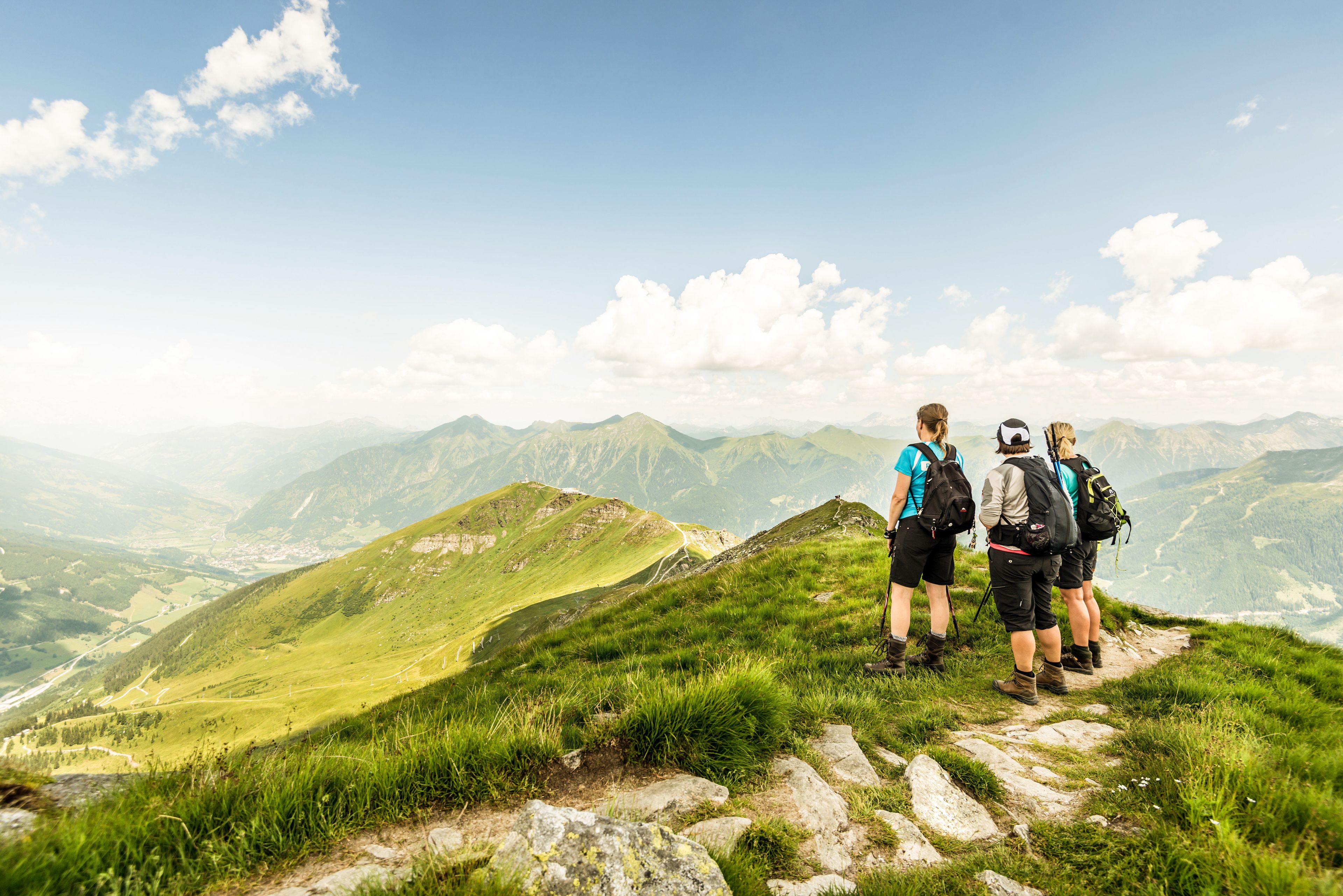 Um grupo de caminhantes numa trilha de montanha com uma vista panorâmica do vale abaixo.