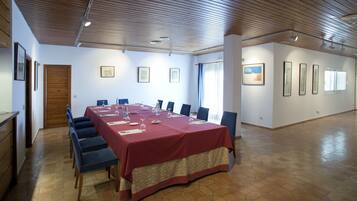 Uma sala de conferências com uma mesa comprida, cadeiras e quadros nas paredes.