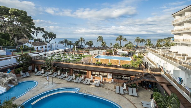 Um resort com várias piscinas, espreguiçadeiras e vista para o mar.
