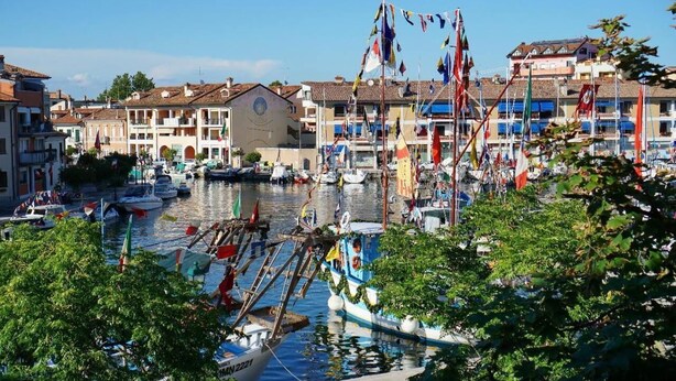 Um porto com barcos atracados, edifícios com varandas e céu claro.