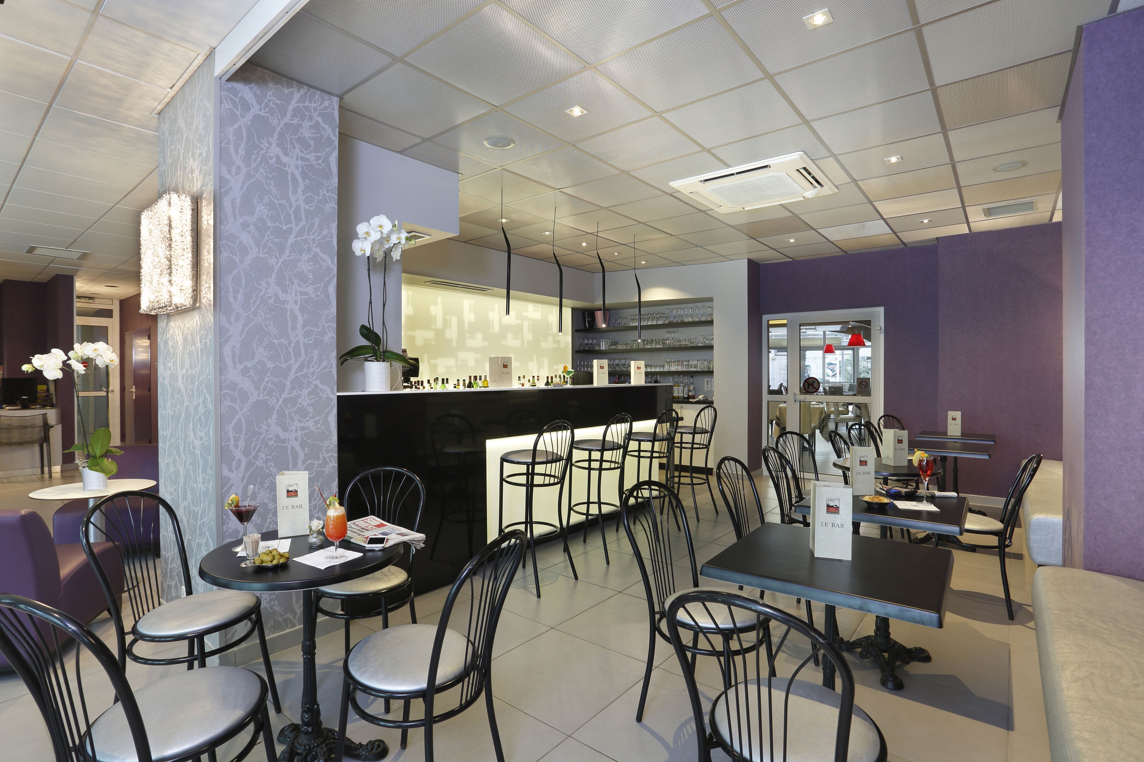 Um restaurante moderno com área de bar, várias mesas de jantar e cadeiras pretas.