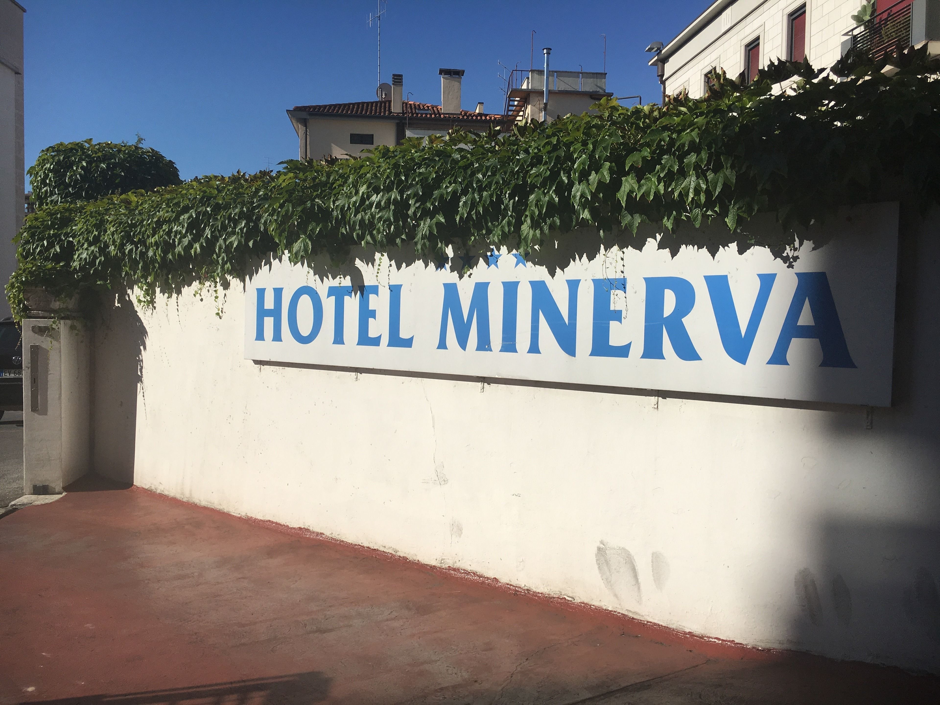 Paredes brancas com o texto "HOTEL MINERVA" em letras azuis.