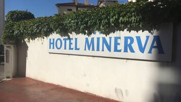 Paredes brancas com o texto "HOTEL MINERVA" em letras azuis.