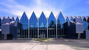 Um edifício moderno com fachada simétrica, grandes janelas de vidro e entrada central.