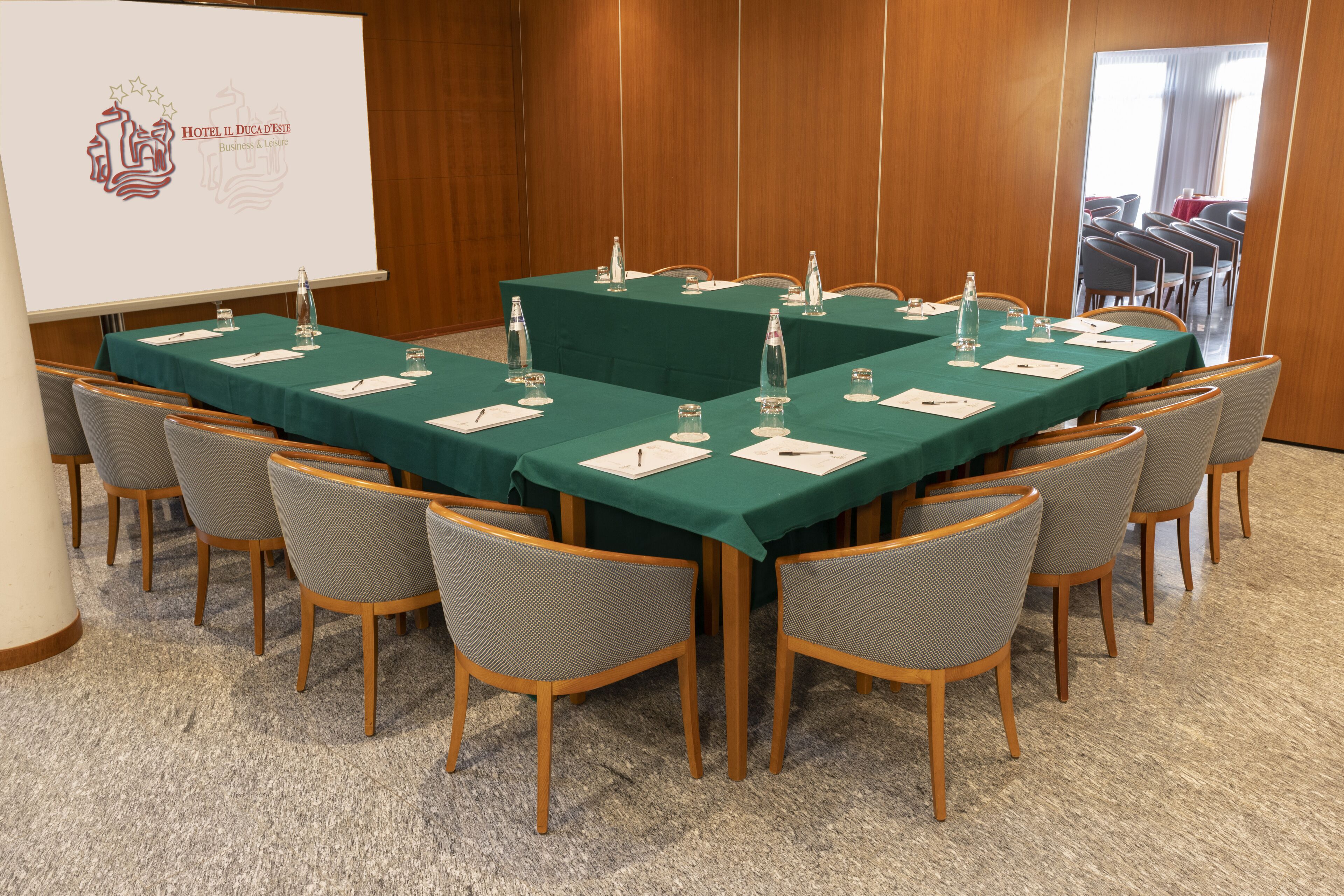 Uma sala de conferência com uma mesa comprida, cadeiras e um quadro branco.