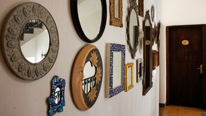 Paredes com vários espelhos emoldurados e objetos decorativos.