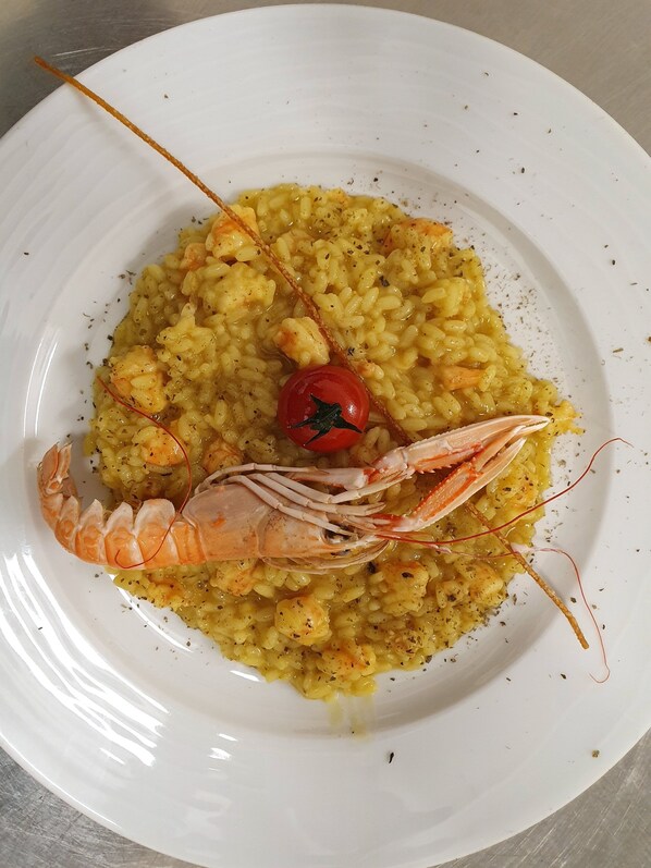 Um prato de risoto com camarão e tomate cereja como guarnição.