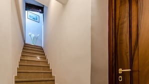 Escada que leva a um quarto com porta de madeira e quadro pendurado na parede.