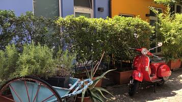 Uma scooter vermelha estacionada ao lado de um carrinho azul com plantas.