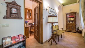 Quarto com armário de madeira, uma cadeira, uma mesa e uma parede com quadros.