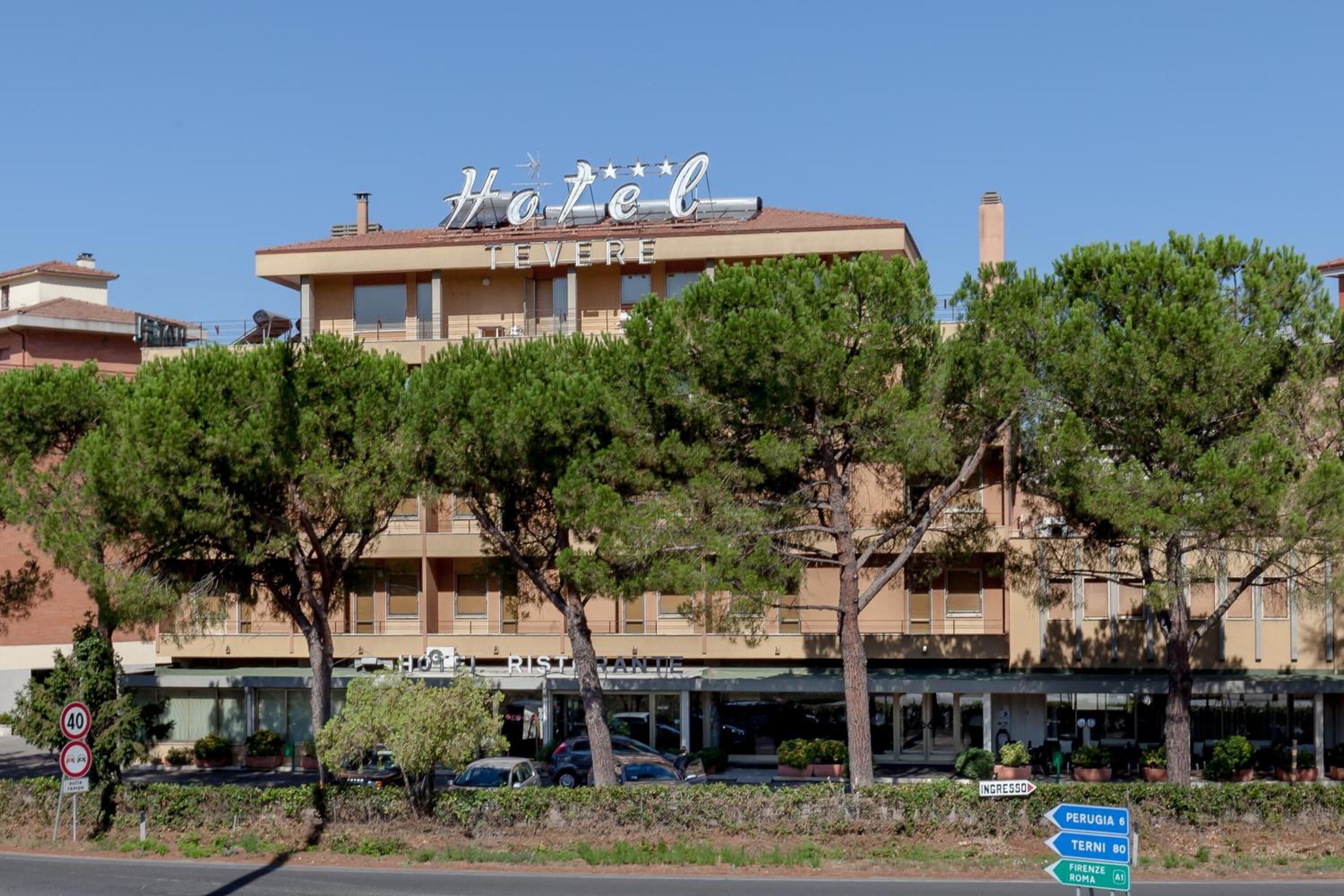 Um hotel com uma placa que diz 'Hotel Tevere' e um restaurante chamado 'Ristorante' logo abaixo.