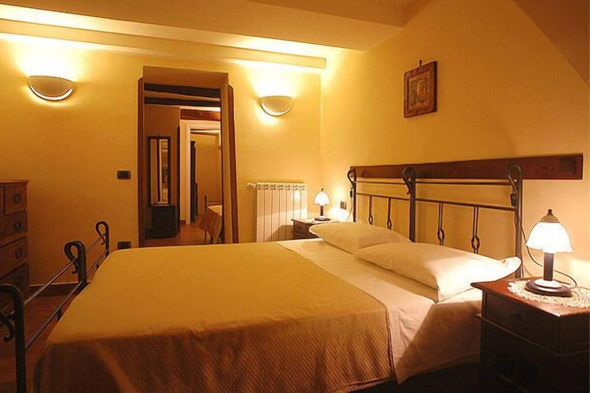 Quarto de hotel com cama, mesas de cabeceira, cômoda e espelho.